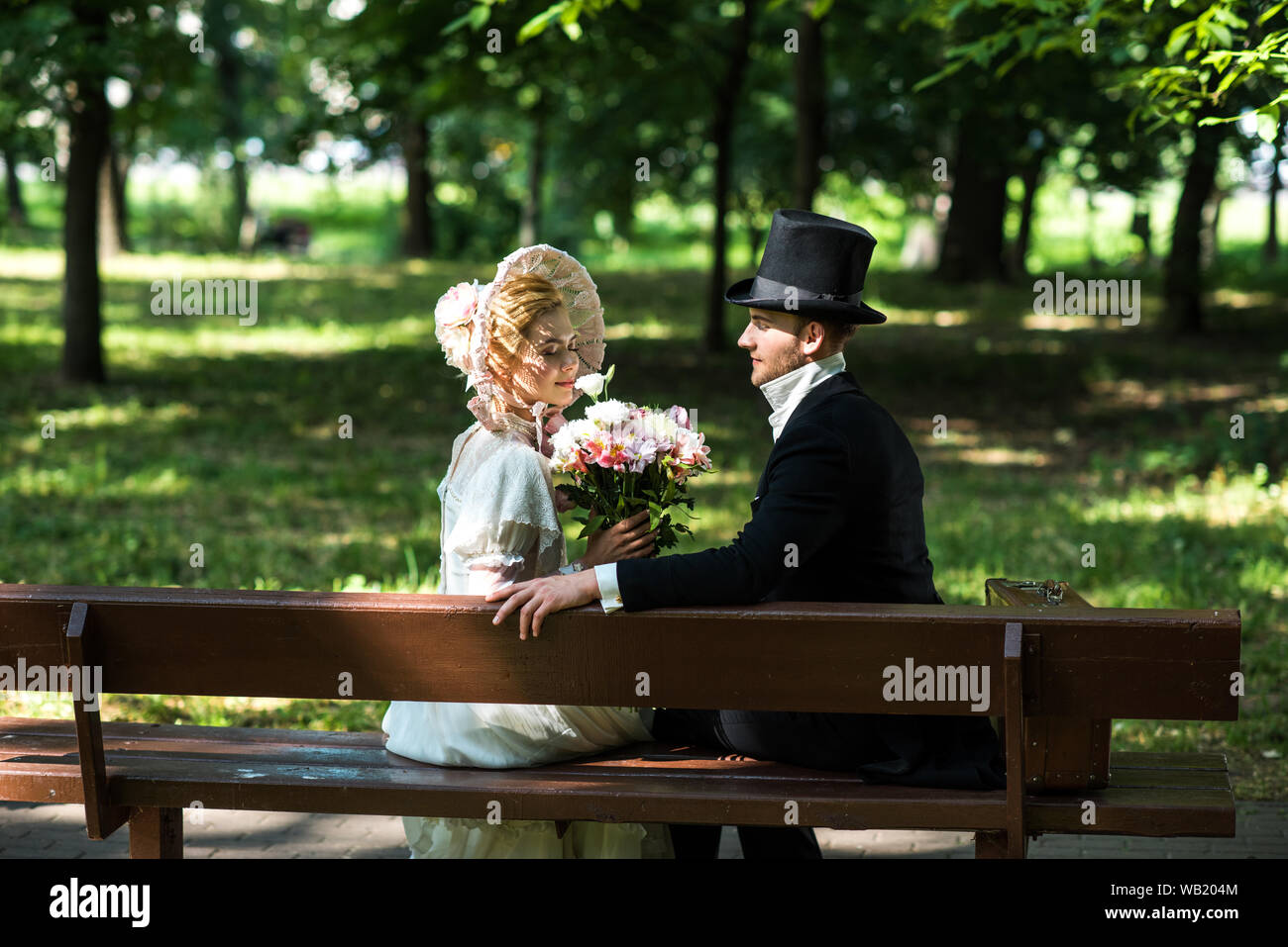 handsome aristocratic man sitting with cheerful victorian woman in hat ...