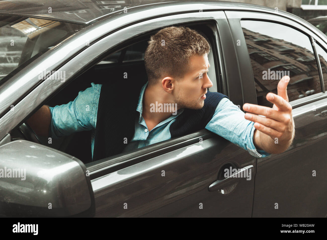 young handsome man looks angry having argument with other drivers ...