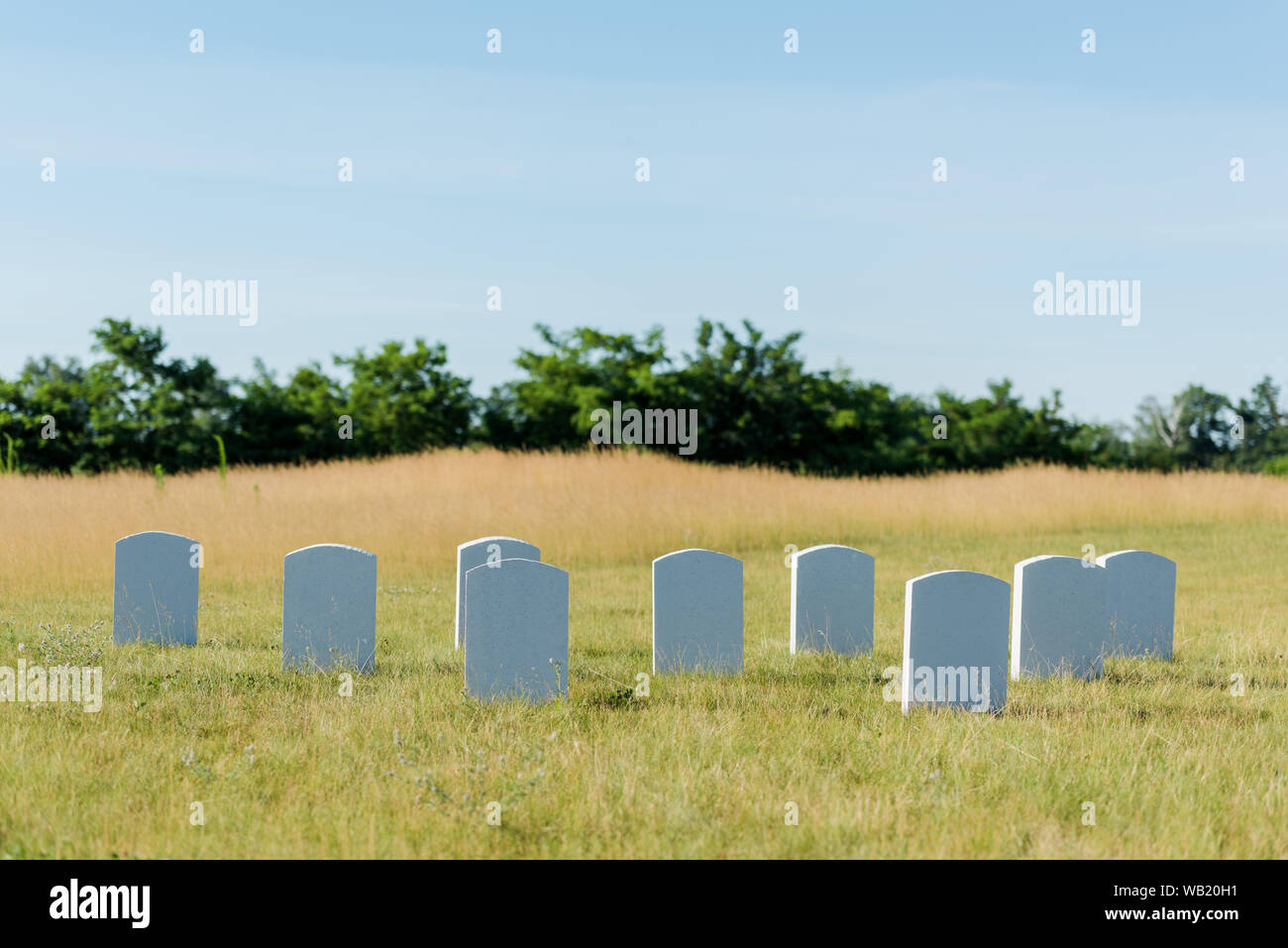 tombstones on green grass and blue sky in graveyard Stock Photo - Alamy