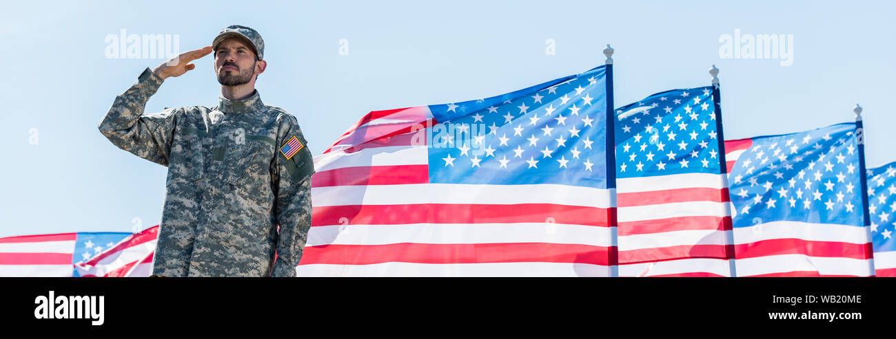 panoramic shot of patriotic soldier in military uniform giving salute ...