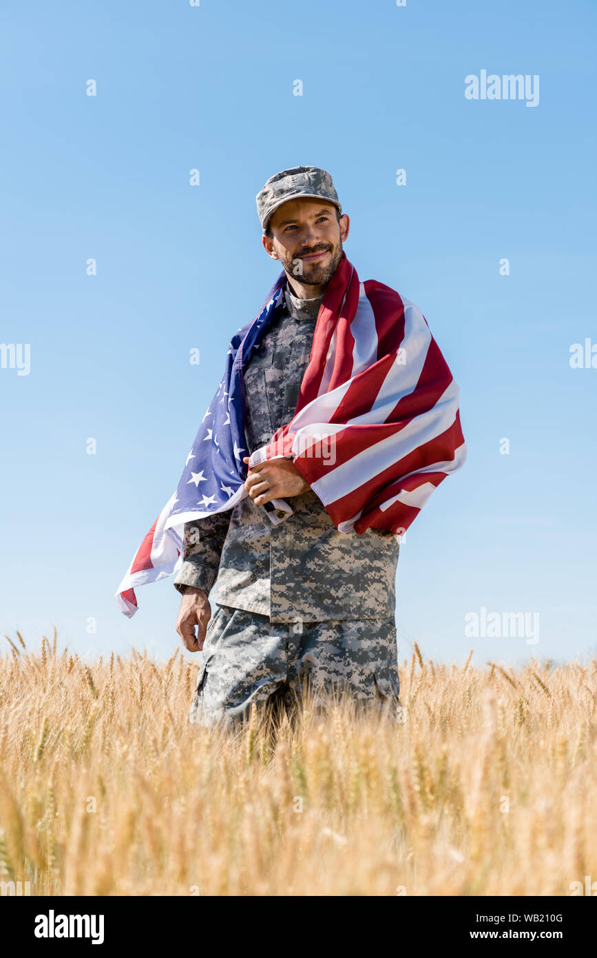 selective focus of happy soldier in cap and uniform holding american ...