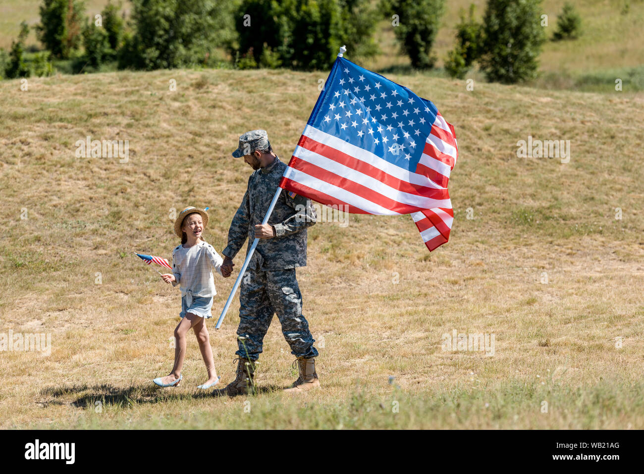 military man and happy patriotic kid holding hands and american flags ...