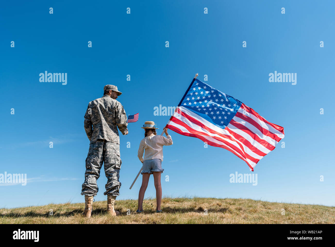 soldier in military uniform standing near kid with american flag ...