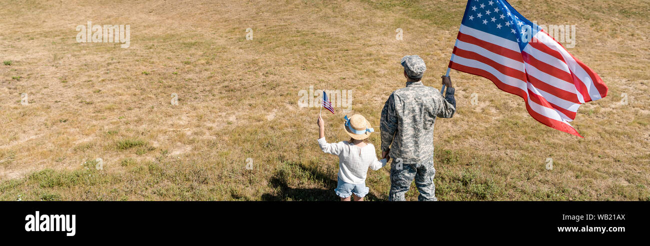 panoramic shot of military man and patriotic kid holding american flags ...