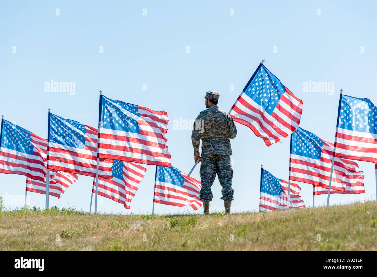 selective focus of soldier in military uniform and cap standing and ...