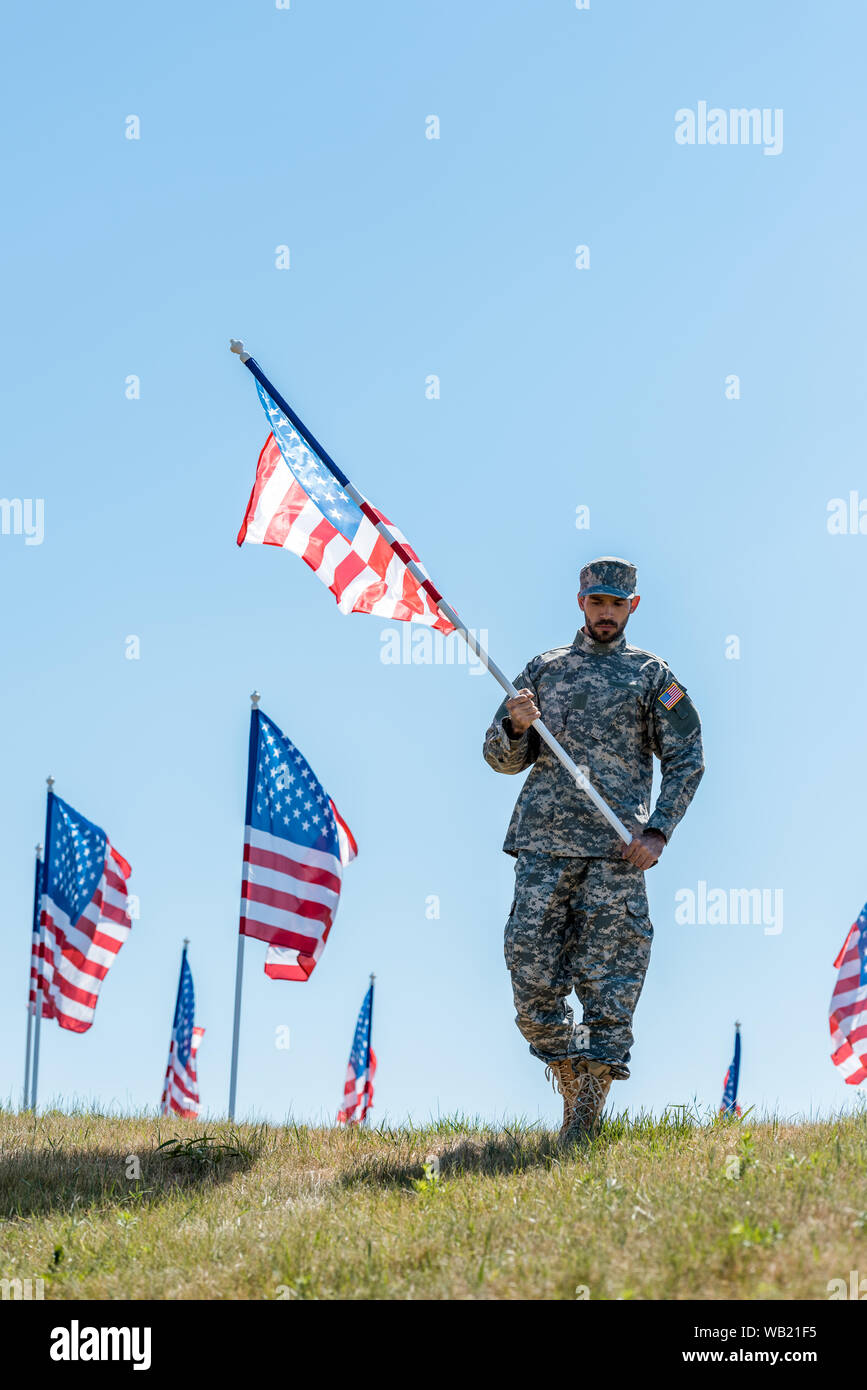handsome soldier in military uniform and cap holding american flag ...
