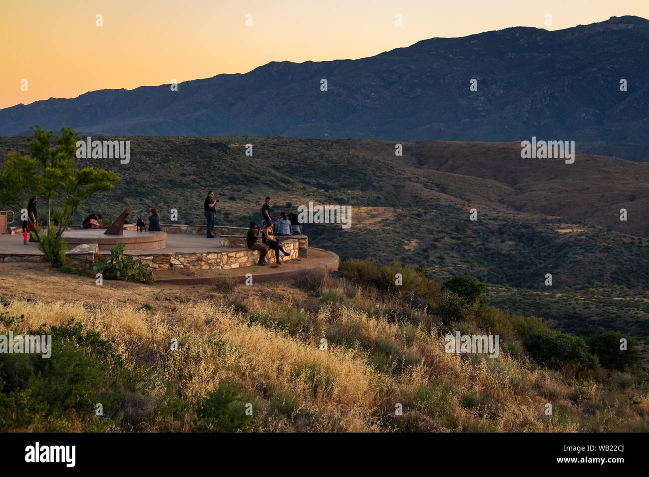 Road travelers watching and photographing the sunset and mountains from ...