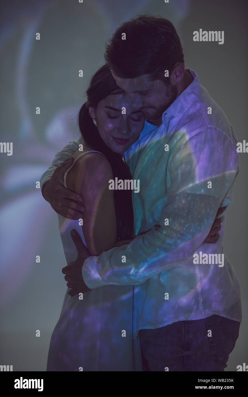beautiful couple hugging while standing in light from projector Stock ...