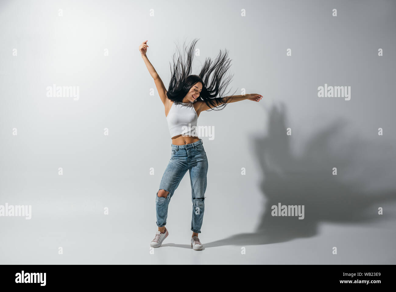 full length view of girl dancing with hands in air on white background ...