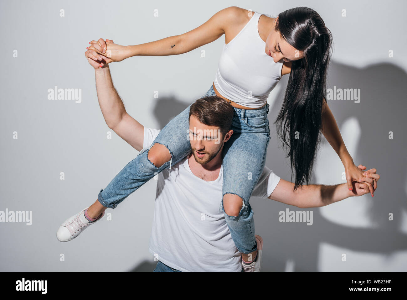 young man holding girlfriend on shoulders while smiling and holding ...
