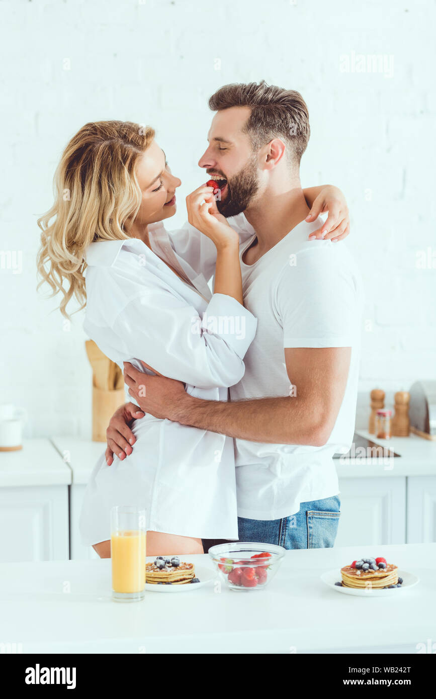 young couple embracing while girlfriend feeding boyfriend with ...