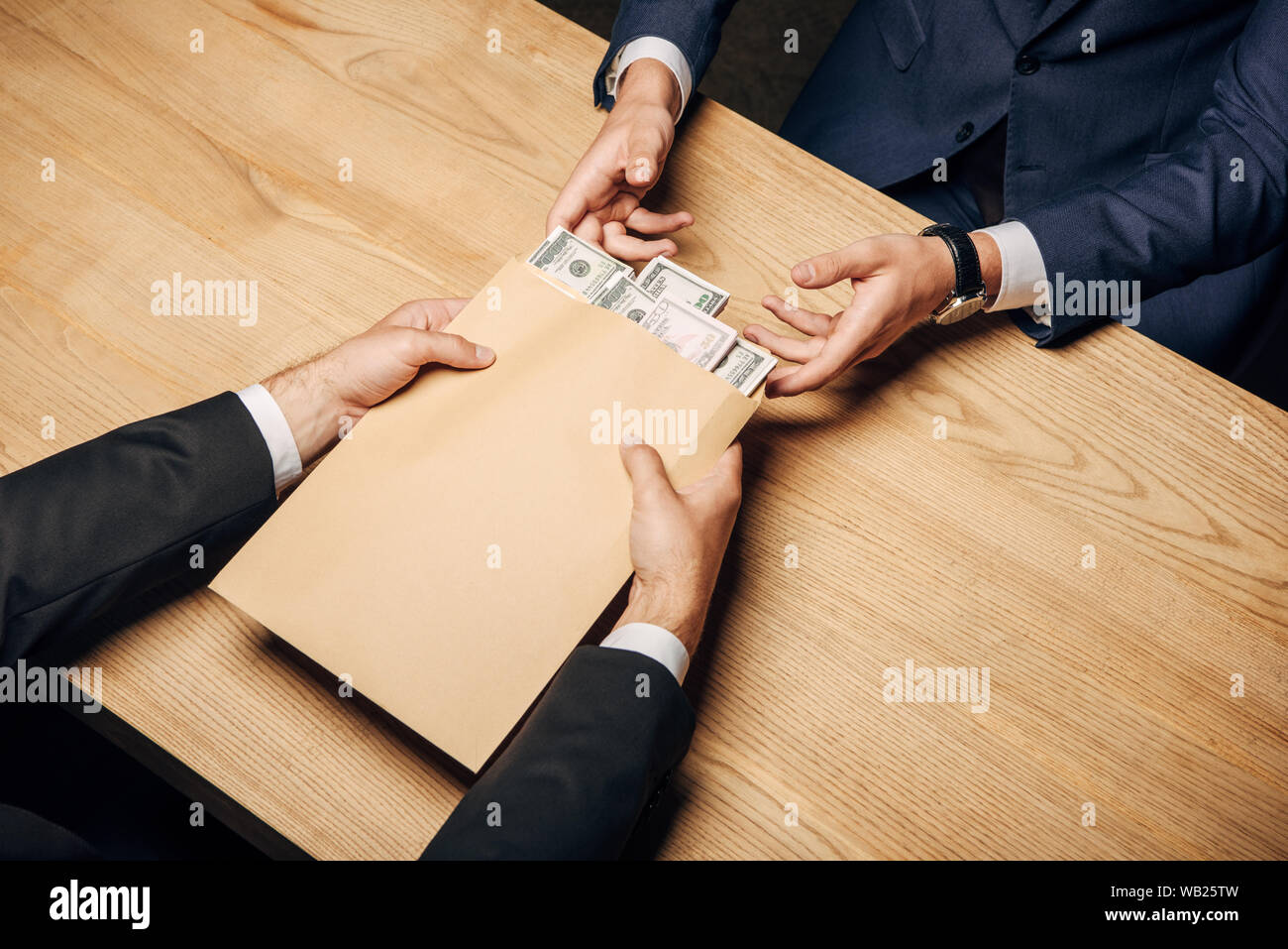 top view man giving envelope with bribe to judge near wooden table ...
