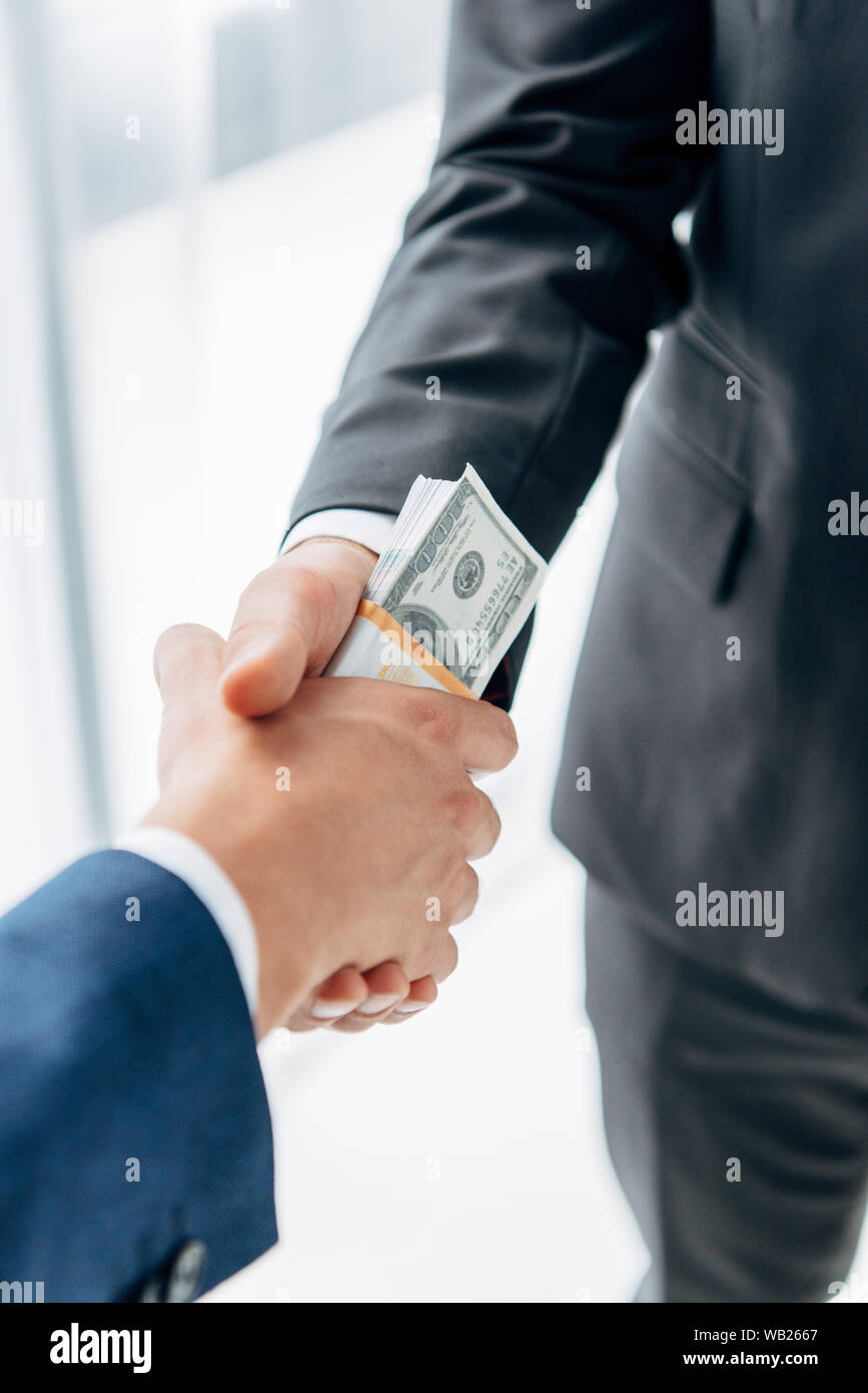 cropped view of businessman giving bribe to business partner while ...