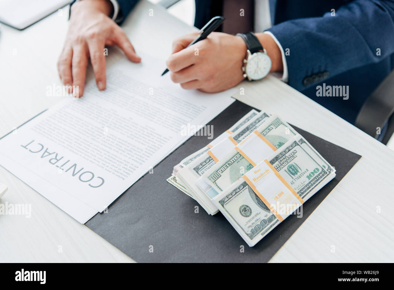 selective focus of dollar banknotes near businessman signing contract ...
