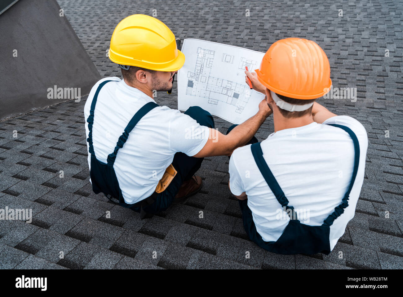 overhead view of builders in helmets looking at blueprint Stock Photo ...