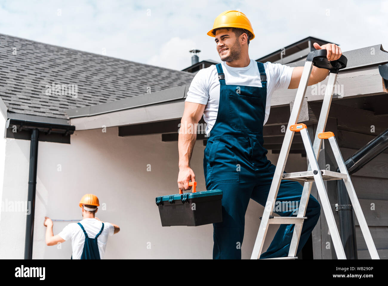 selective focus of happy workman standing on ladder with toolbox near ...