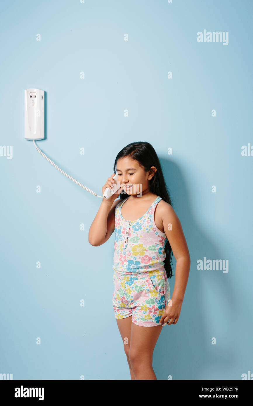 9-year old girl is standing over light blue background. She's speaking ...