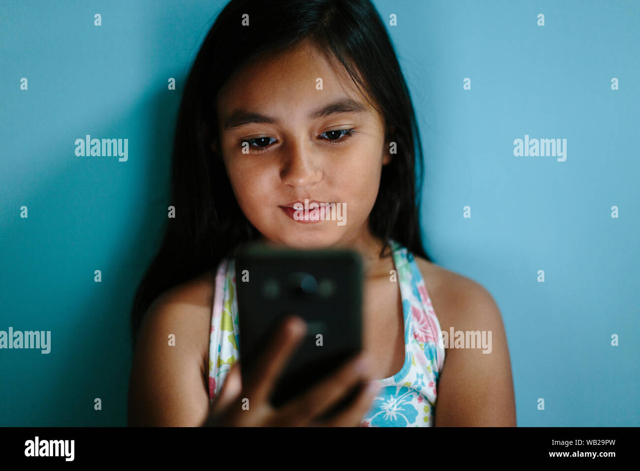 9 Year Old Girl Is Sitting On The Floor Leaning Her Back Over A Blue