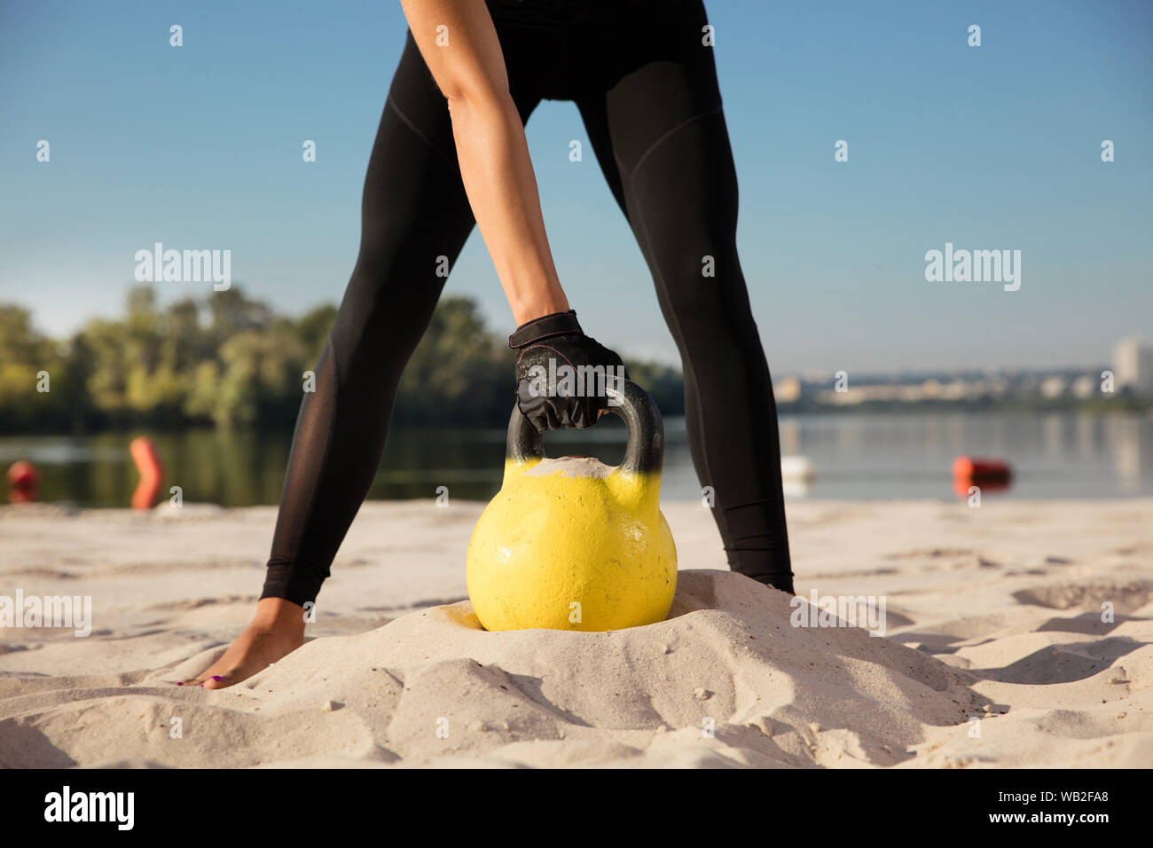 Young healthy woman training upper body with weights at the beach ...