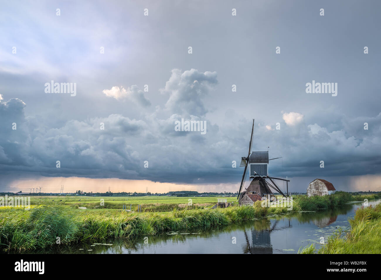 Classic dutch scene of a windmill and stormy clouds over the polder ...