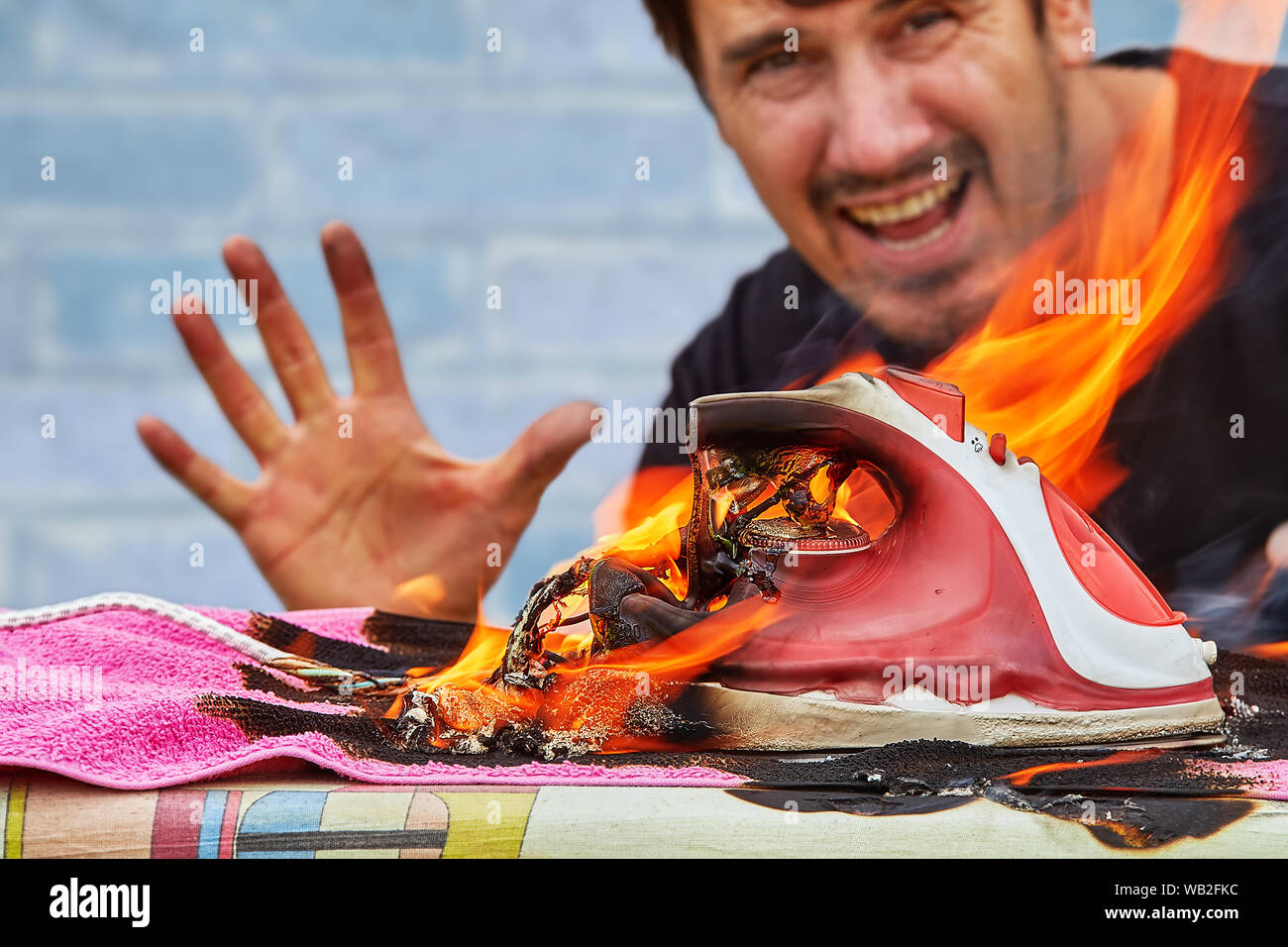 A man is trying to extinguish a household fire, an electric iron for ...