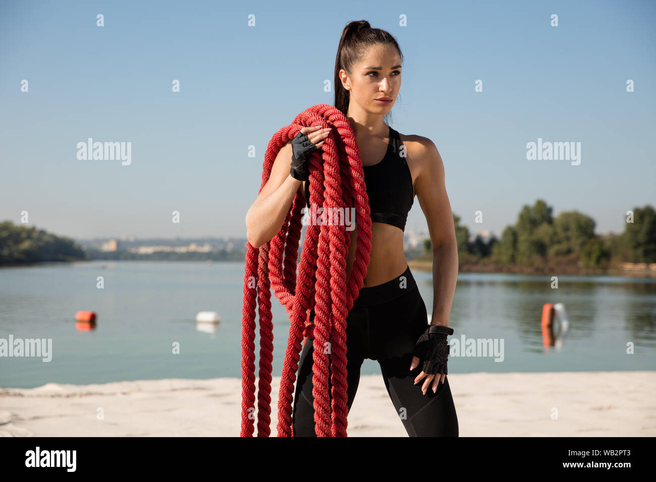 Young healthy woman posing with the ropes at the beach. Single ...