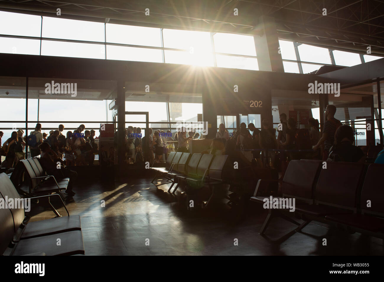 Passengers waiting in line for departure in an airport's waiting hall ...