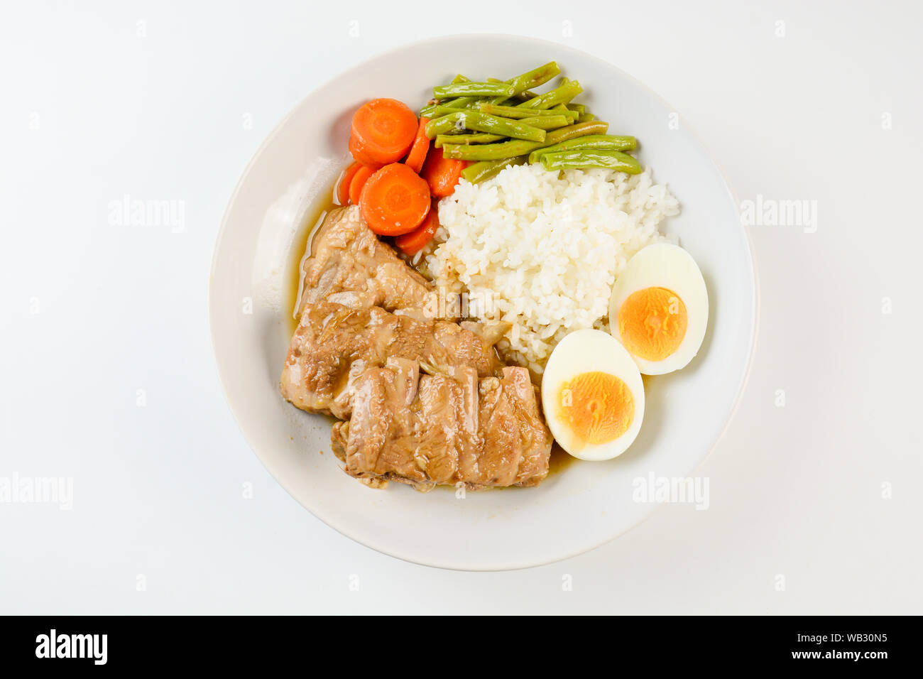 Baked pork ribs with rice, boiled egg and vegetable Stock Photo - Alamy