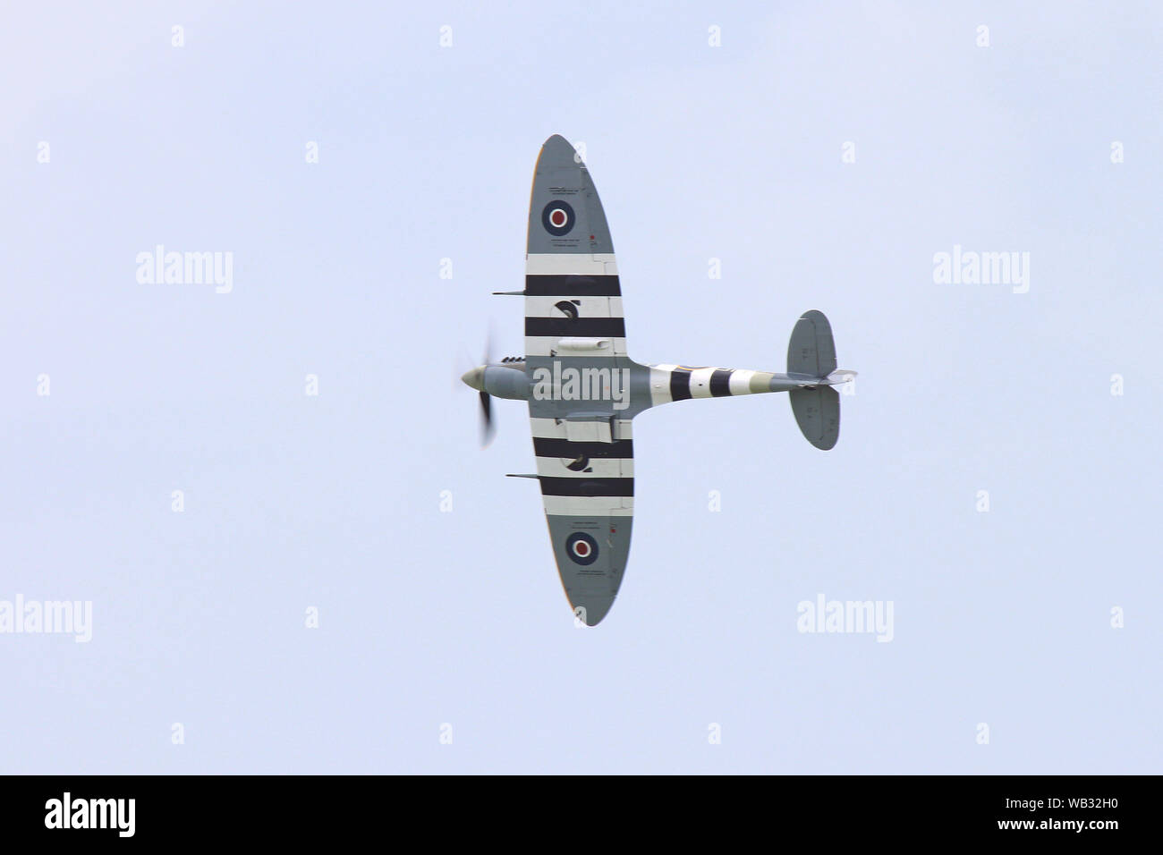 A Spitfire passes overhead showing its elliptical wings. The stripes ...