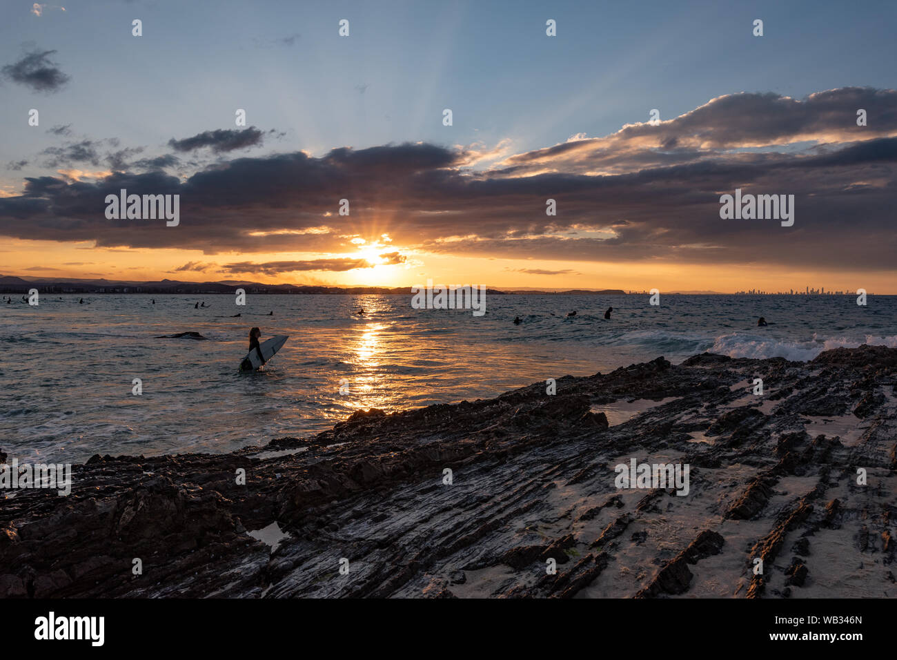 Surfer standing inside water during sunset at Snapper Rocks Stock Photo ...