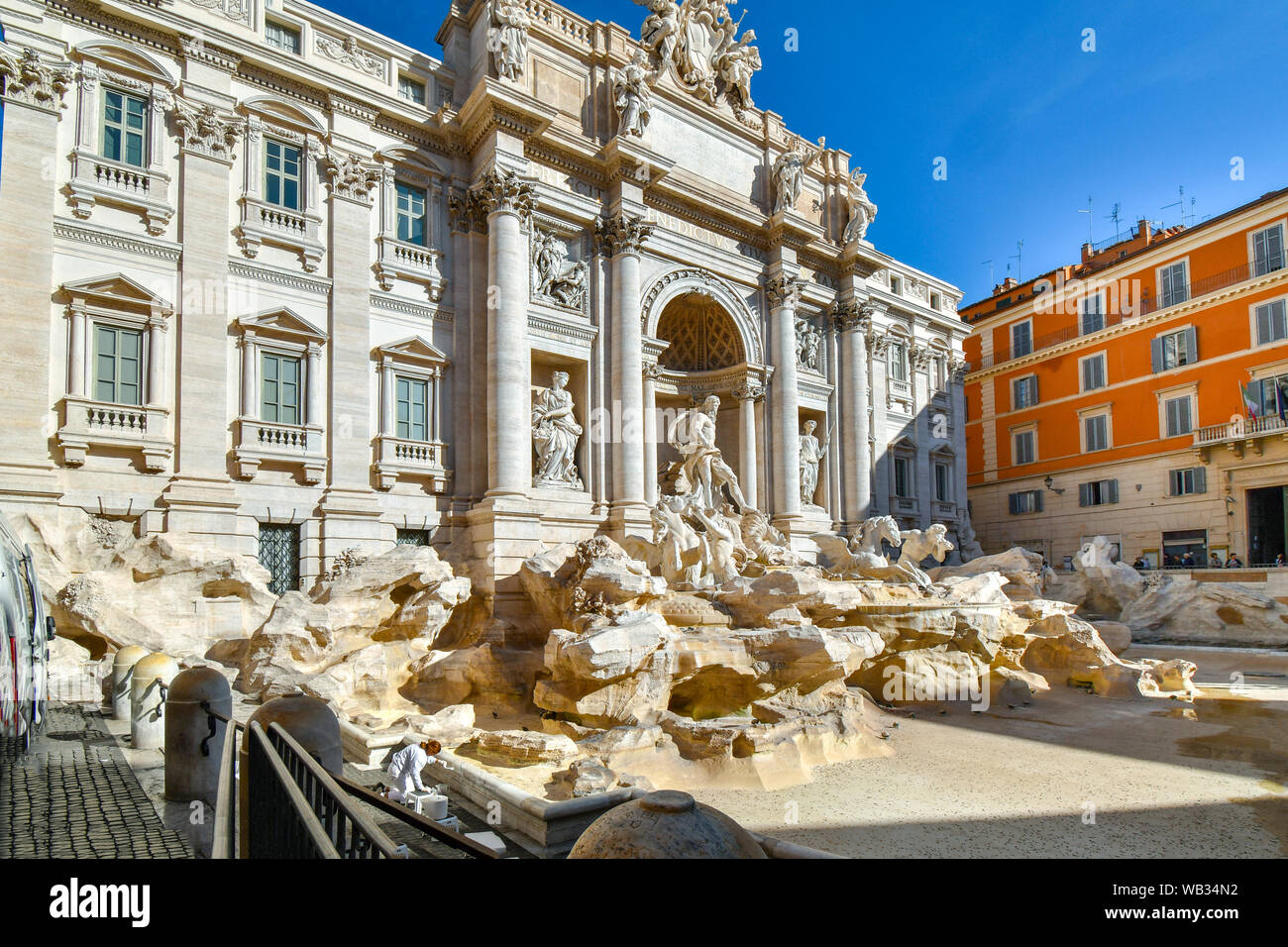 Workers and art historians clean and do maintenance on an empty Trevi ...
