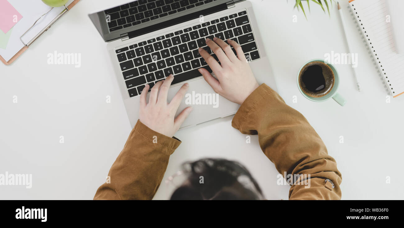 Top view with white desk background of woman typing on laptop computer ...