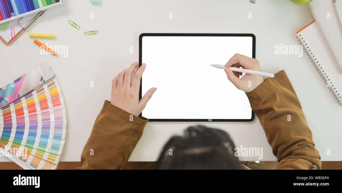 Top view of female graphic designer sketching on blank screen tablet ...