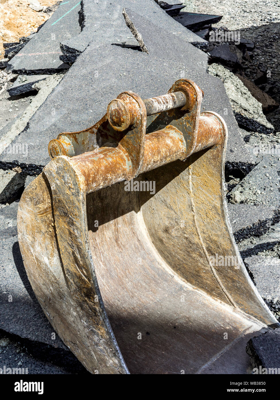 Digger bucket and broken road surface Stock Photo - Alamy