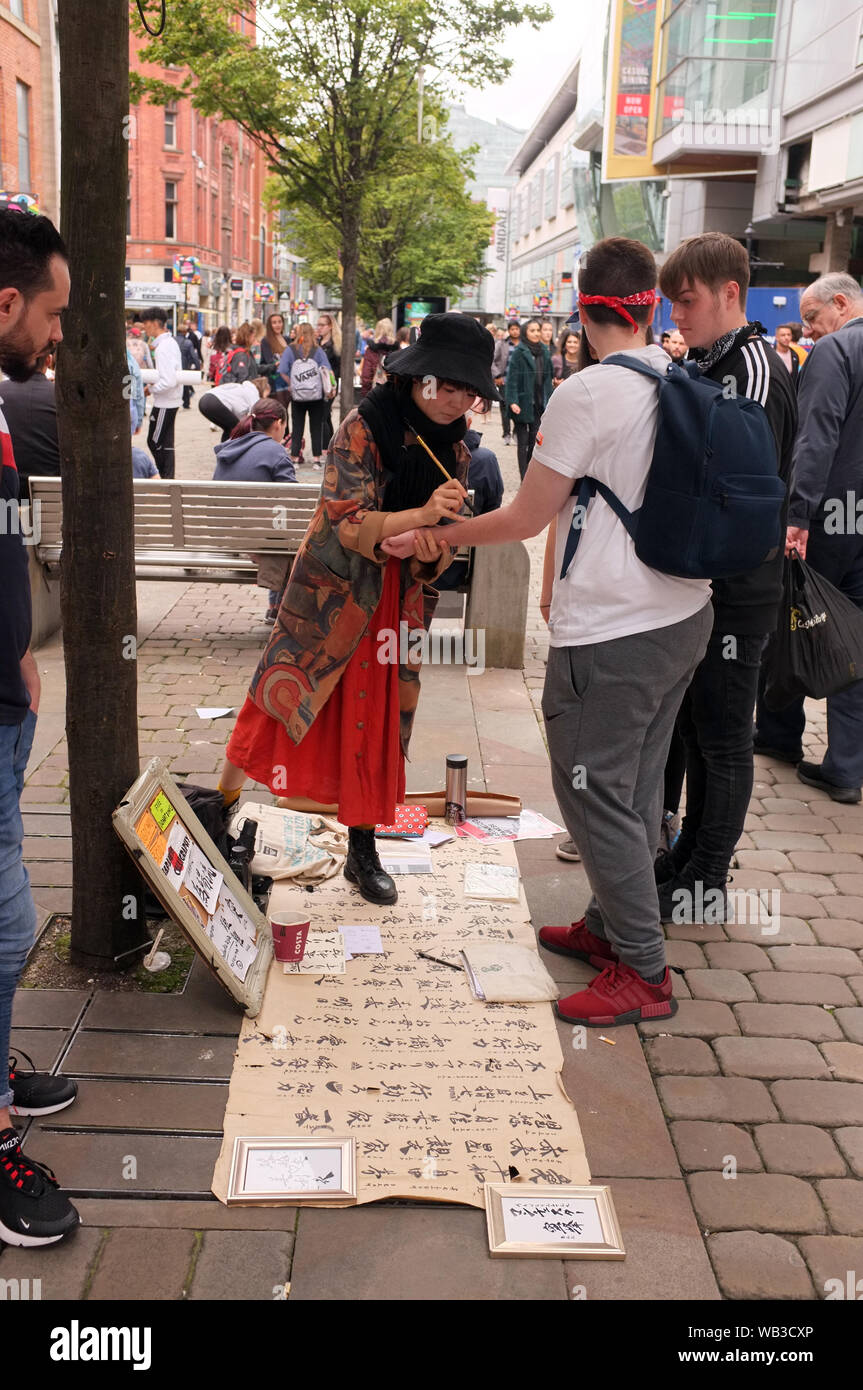 Female calligraphy artist on Market Street Manchester City Centre ...