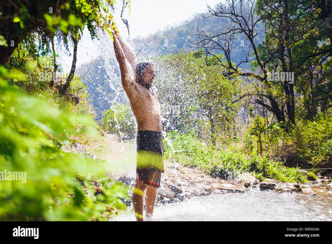 Man washes in a waterfall. Drops of water. Natural pleasure Stock Photo ...