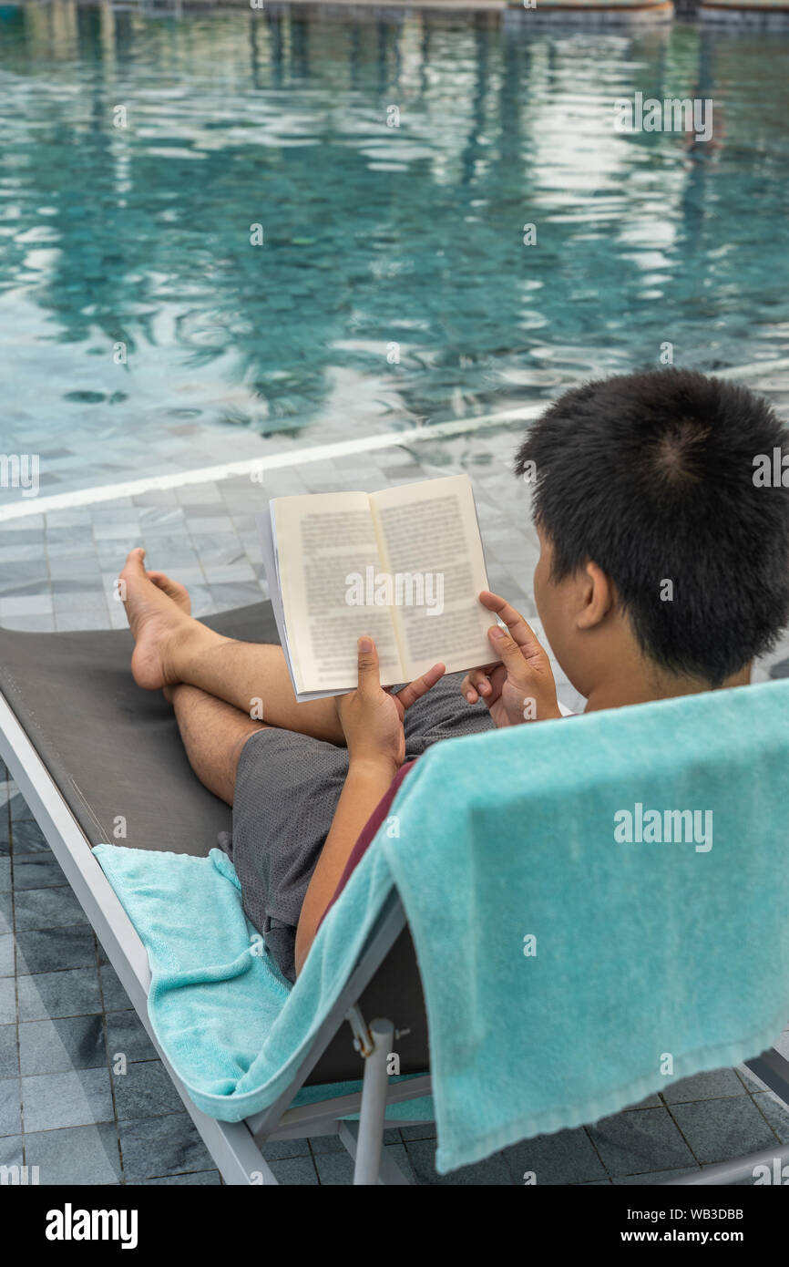 Man reading book at the swimming pool Stock Photo - Alamy