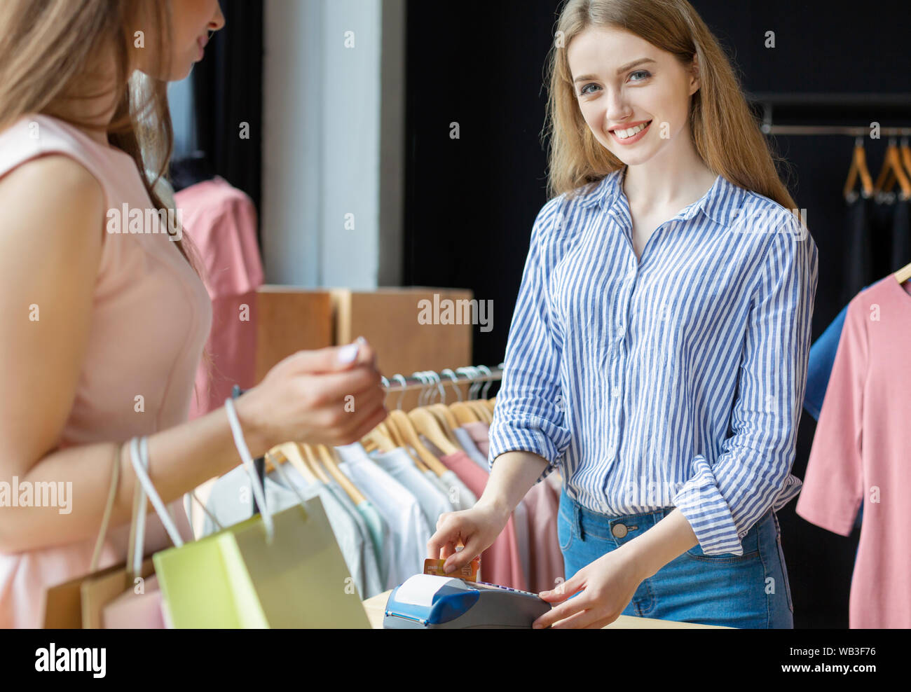 Shop assistant smiling while swiping credit card in clothing shop Stock ...