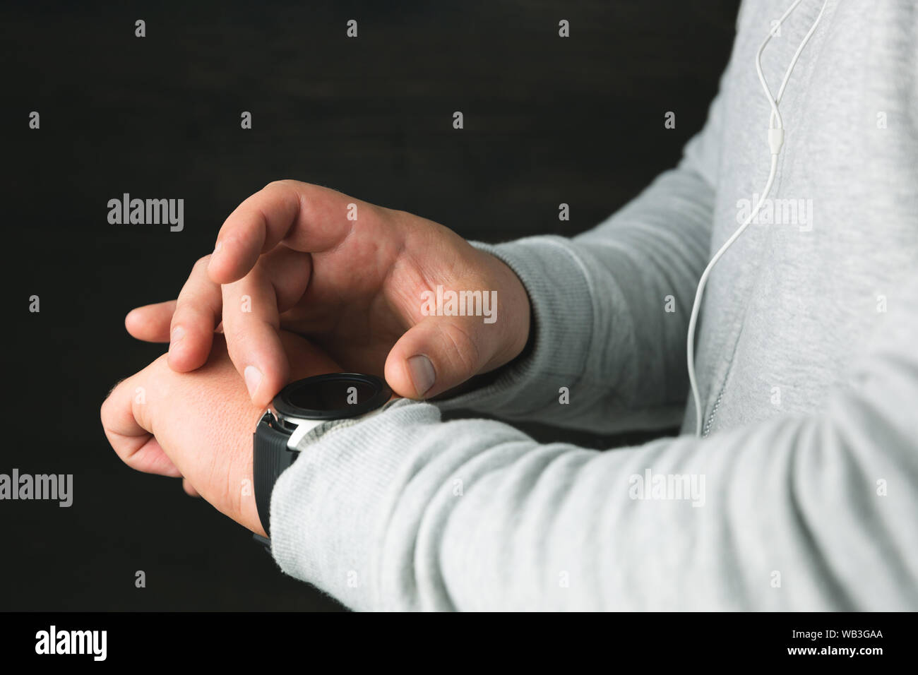 Man in a sport hoodie checking notification on digital smartwatch ...