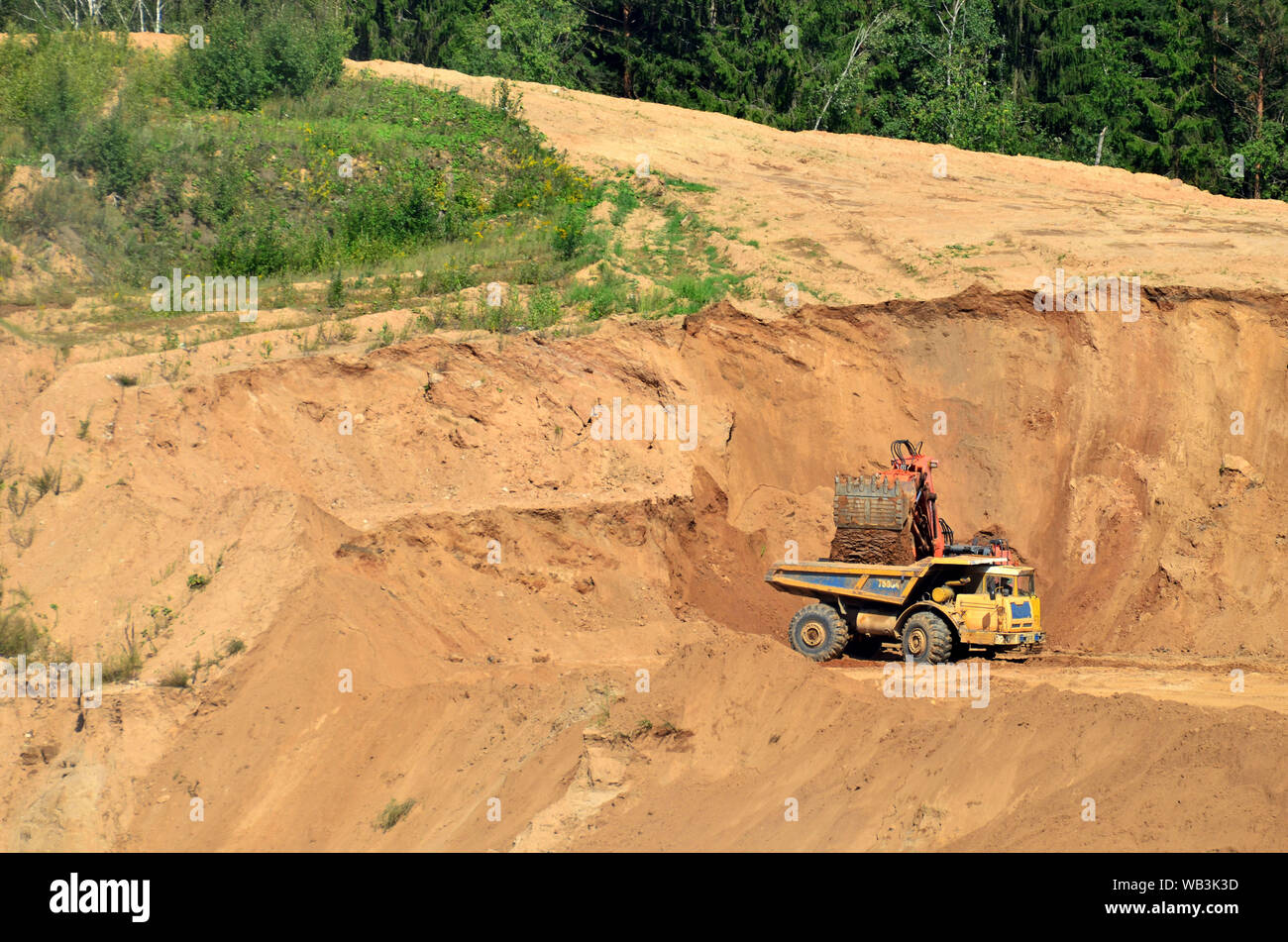 Excavator developing the sand on the opencast and loading it to the ...