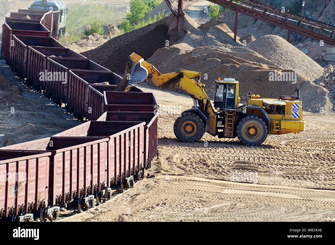 Large heavy front-end loader loading sand it to the freight train Stock ...