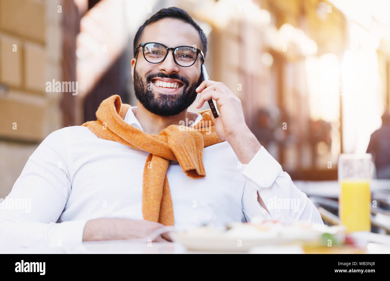 Cheerful multicultural developer making phone call while having dinner ...