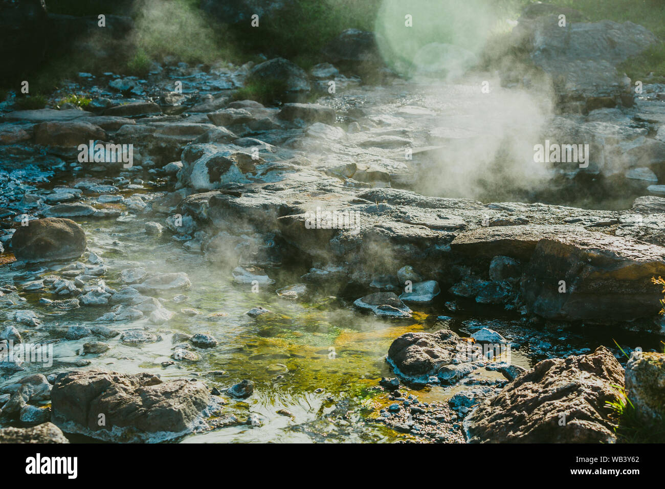 Steam and sulphur rise from a colorful hot spring on the surface of the ...