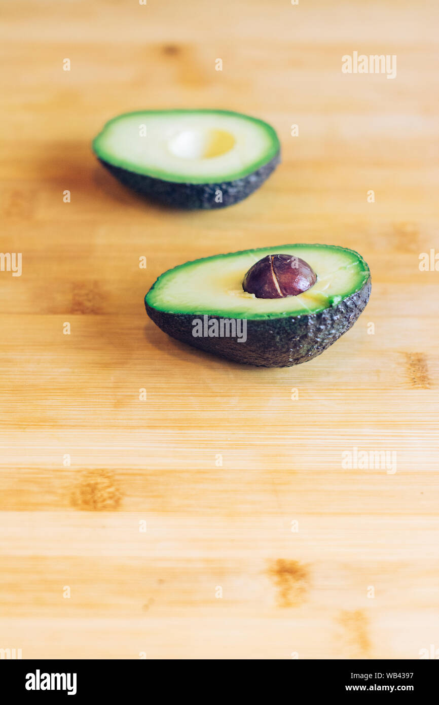 An avocado cut in half, on a table in the kitchen with the seed Stock ...