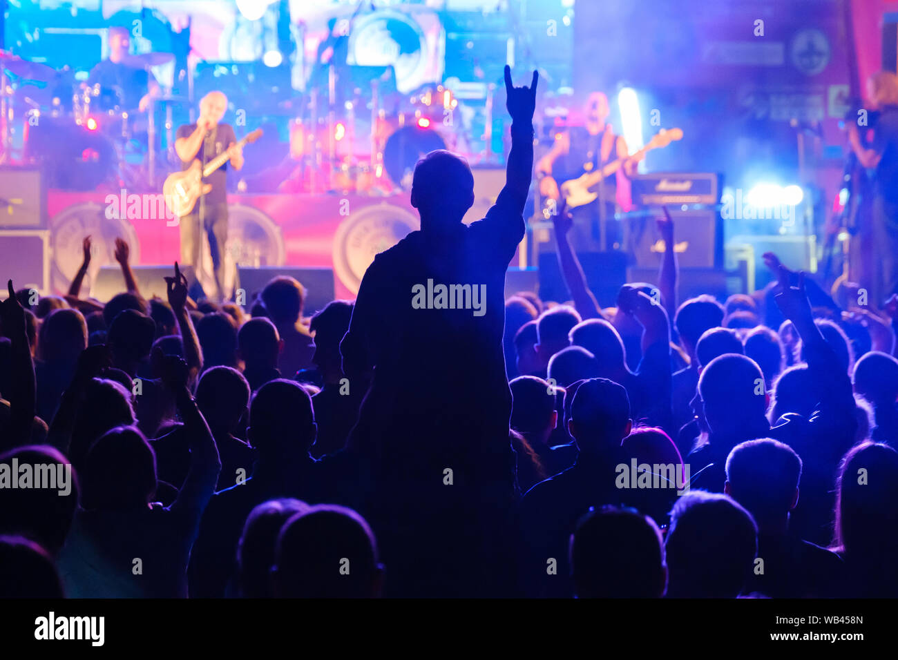 Fans at live rock music concert cheering musicians on stage, back view ...