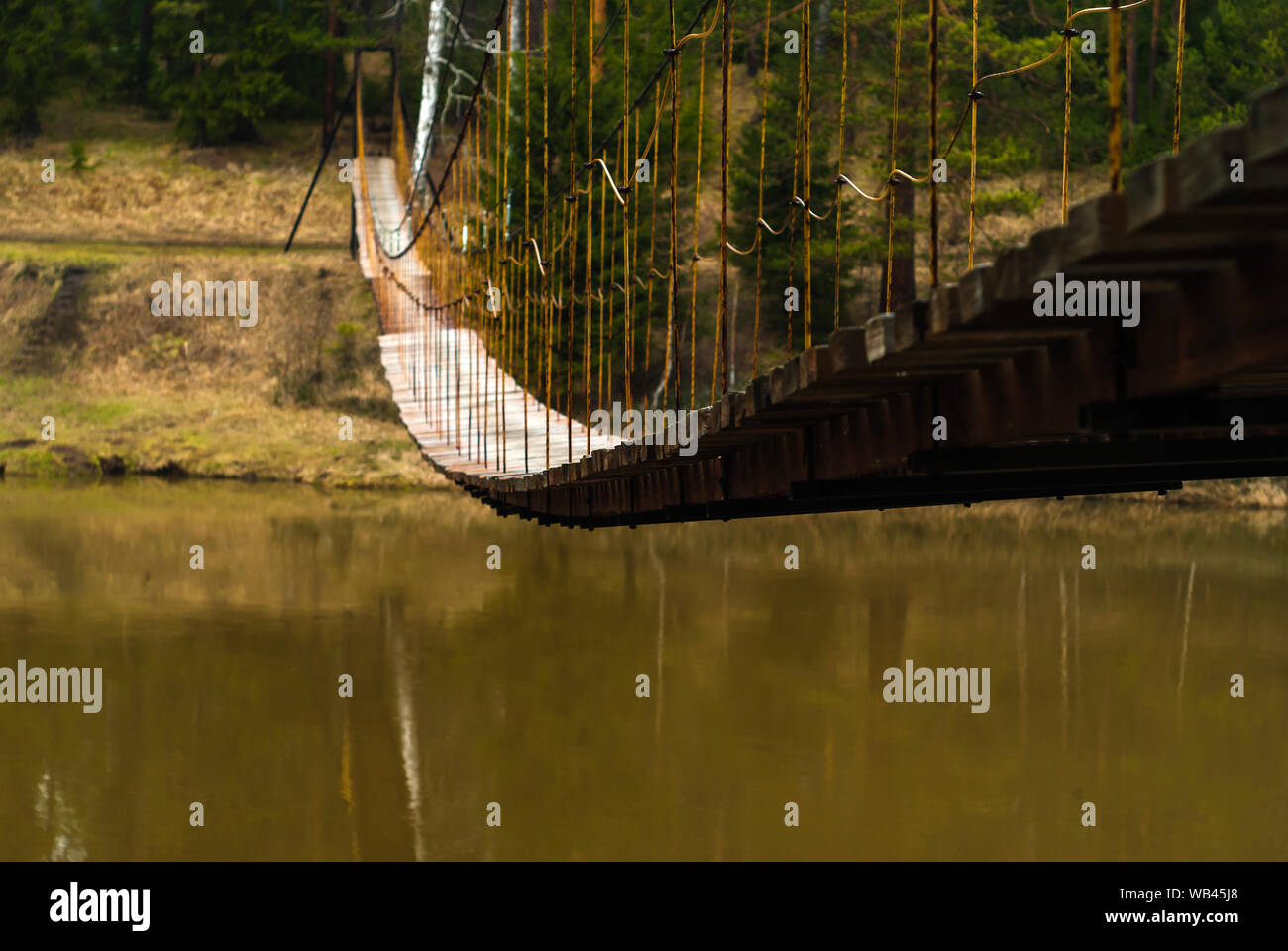 wooden suspension bridge over the muddy spring river close up Stock ...