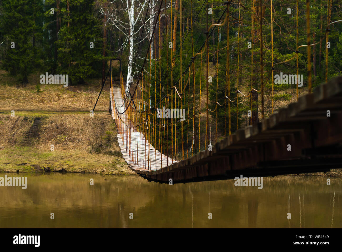 wooden suspension bridge over the muddy spring river Stock Photo - Alamy