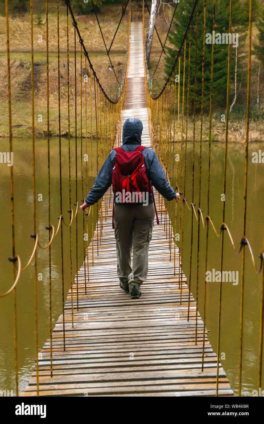 traveler goes along the hanging bridge over the spring river Stock ...