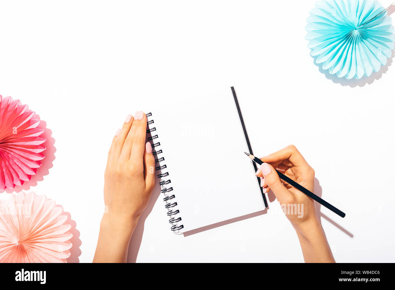 Female's hands writing in empty notepad near festive paper party ...