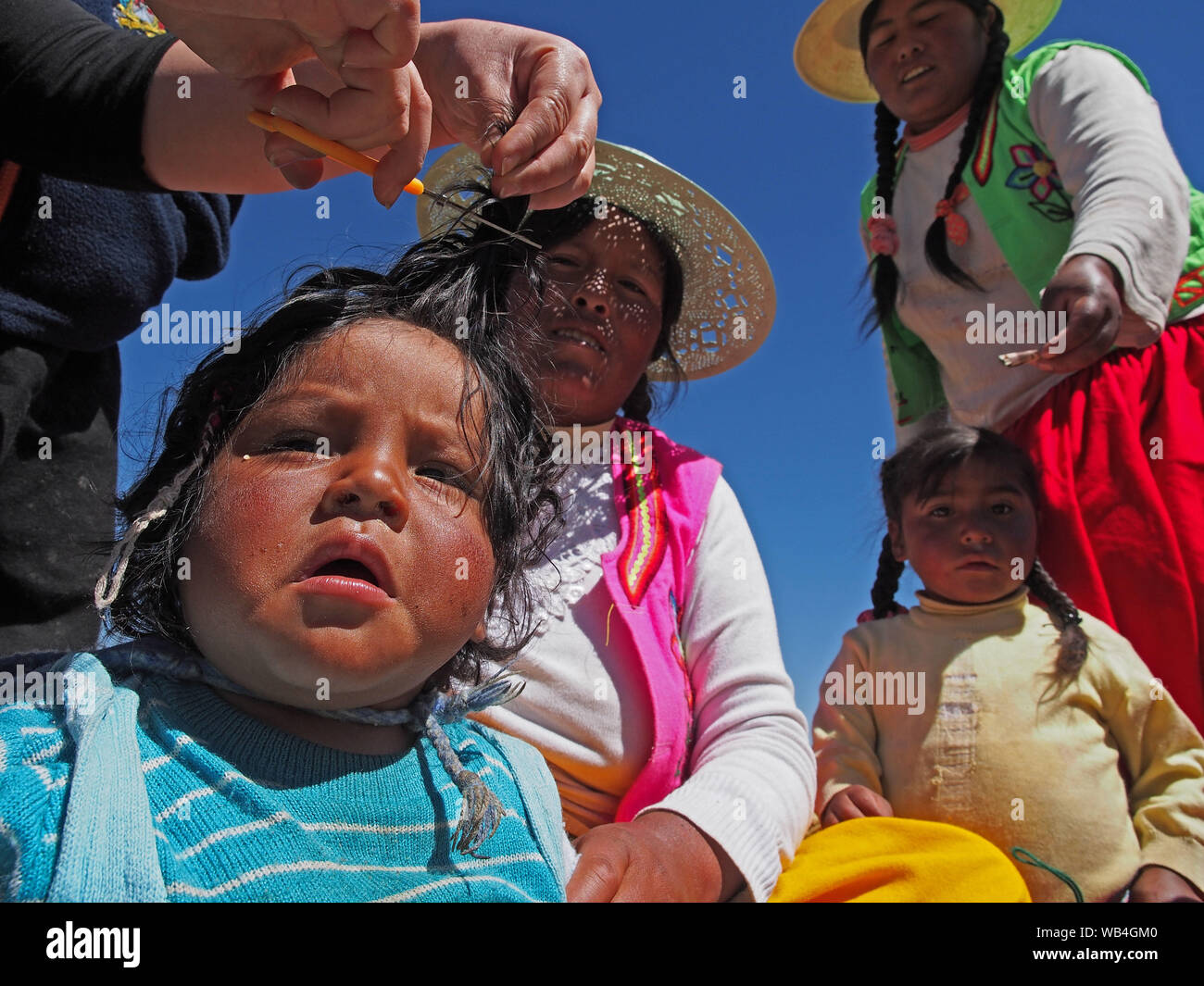 An indigenous child Uro receiving his first haircut surrounded by his ...